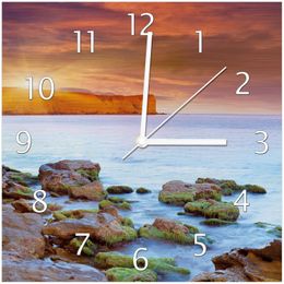 Wallario Wanduhr Sonnenaufgang am Meer mit Landzunge und Felsen im Wasser (Aluverbunduhr), blau, mit weißen Zeigern