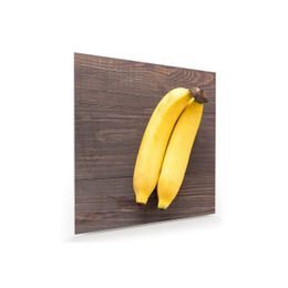 Primedeco Glasbild Wandbild Quadratisch Bananen auf Tisch mit Aufhängung