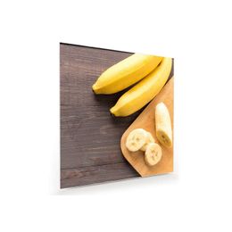 Primedeco Glasbild Wandbild Quadratisch Banane auf Schneidebrett mit Aufhängung