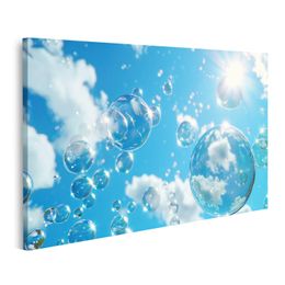 islandburner Leinwandbild Schwebende blaue Blasen gleiten elegant durch den himmelblauen Hinterg