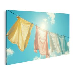 islandburner Leinwandbild Leuchtende Pastelltücher trocknen an einer Leine vor blauem, sonnigen